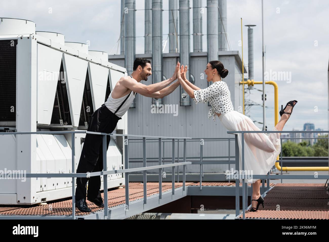 Side view of excited professional dancers giving high five on rooftop ...
