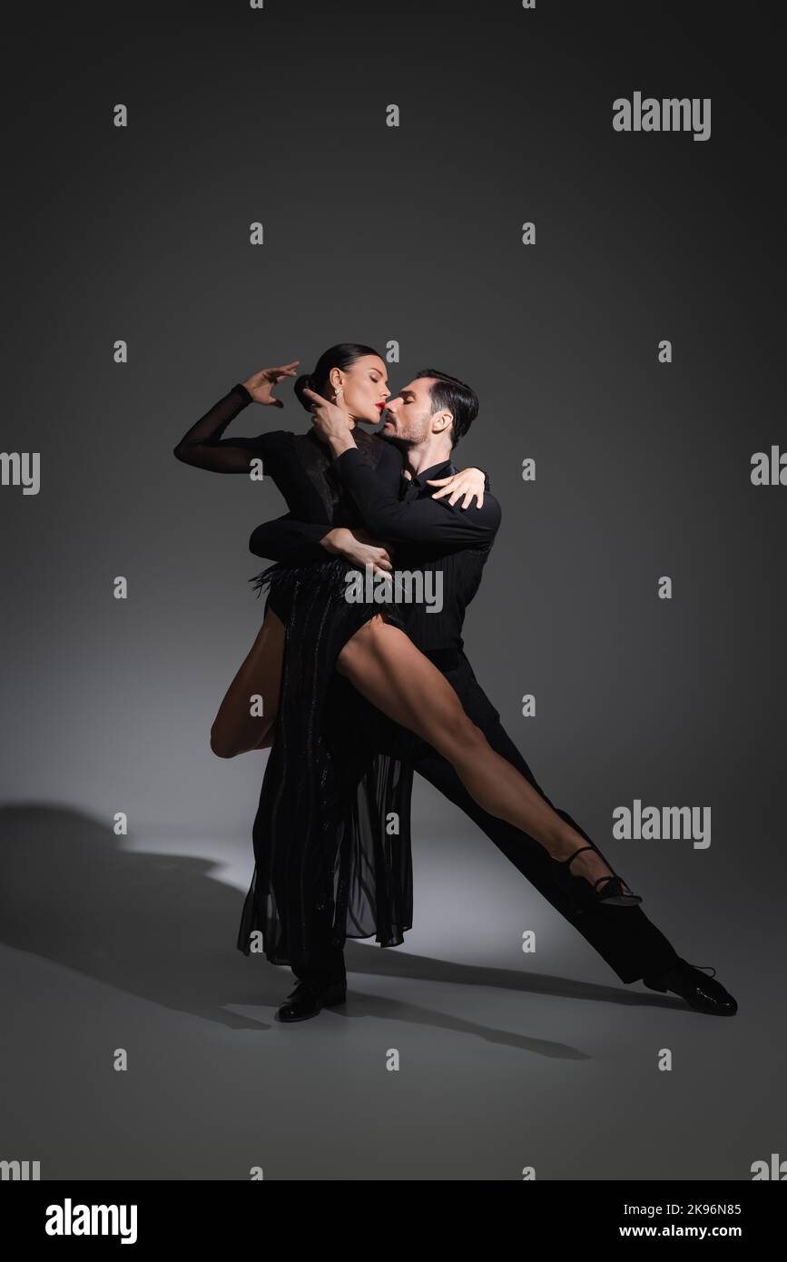 Side view of professional dancers performing tango on grey background ...