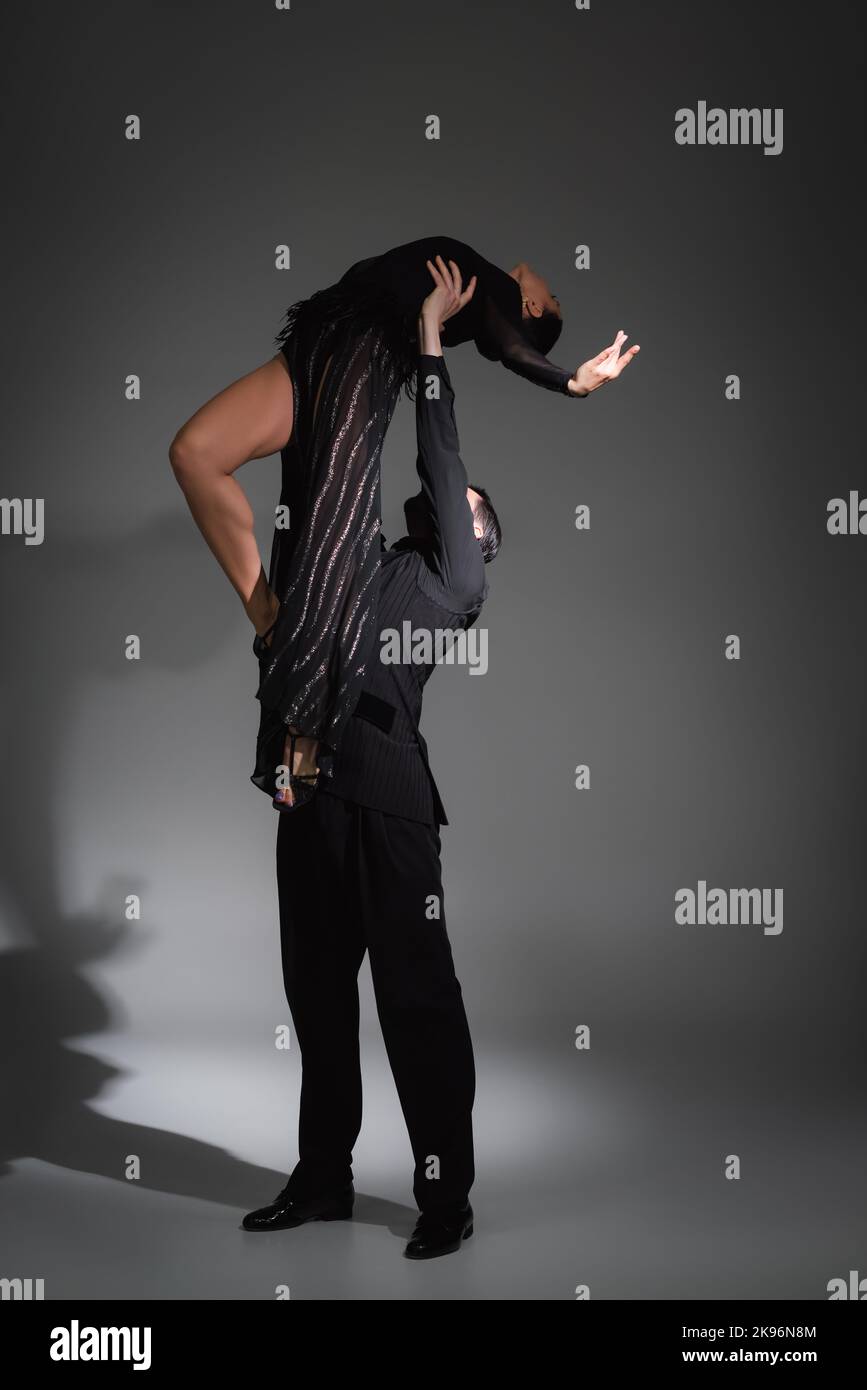 Dancer lifting partner in black dress on grey background with shadow ...