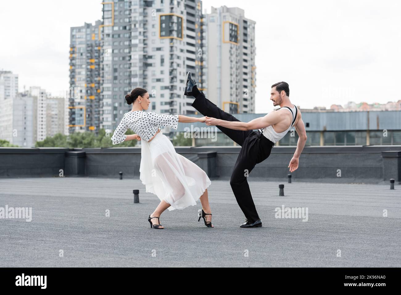 Side view of cheerful professional dancers moving on rooftop of ...