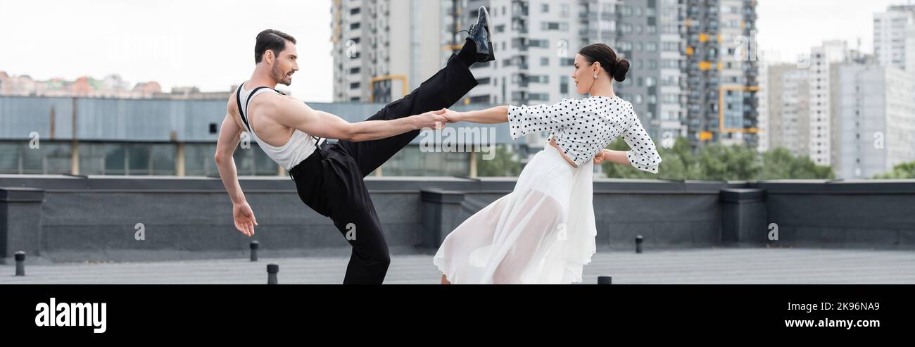Side view of stylish dancers performing choreography on rooftop at ...