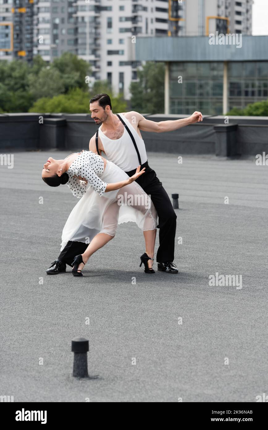 Professional dancer moving with elegant partner on rooftop of building ...
