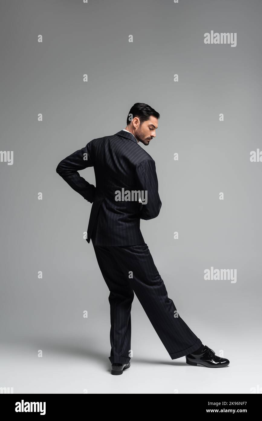 Side view of elegant dancer in suit moving on grey background Stock ...