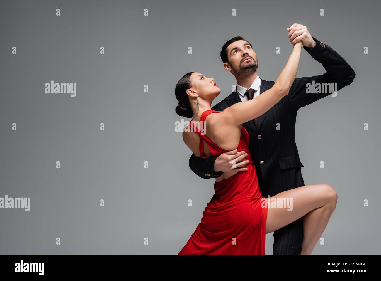Elegant dancers holding hands while dancing tango isolated on grey ...