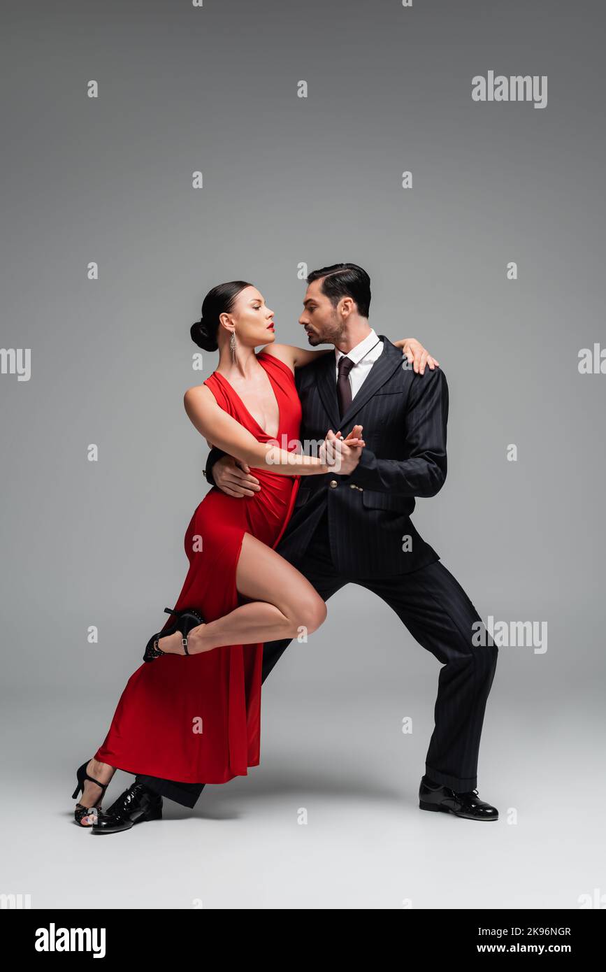 Side view of man dancing tango with elegant partner on grey background ...