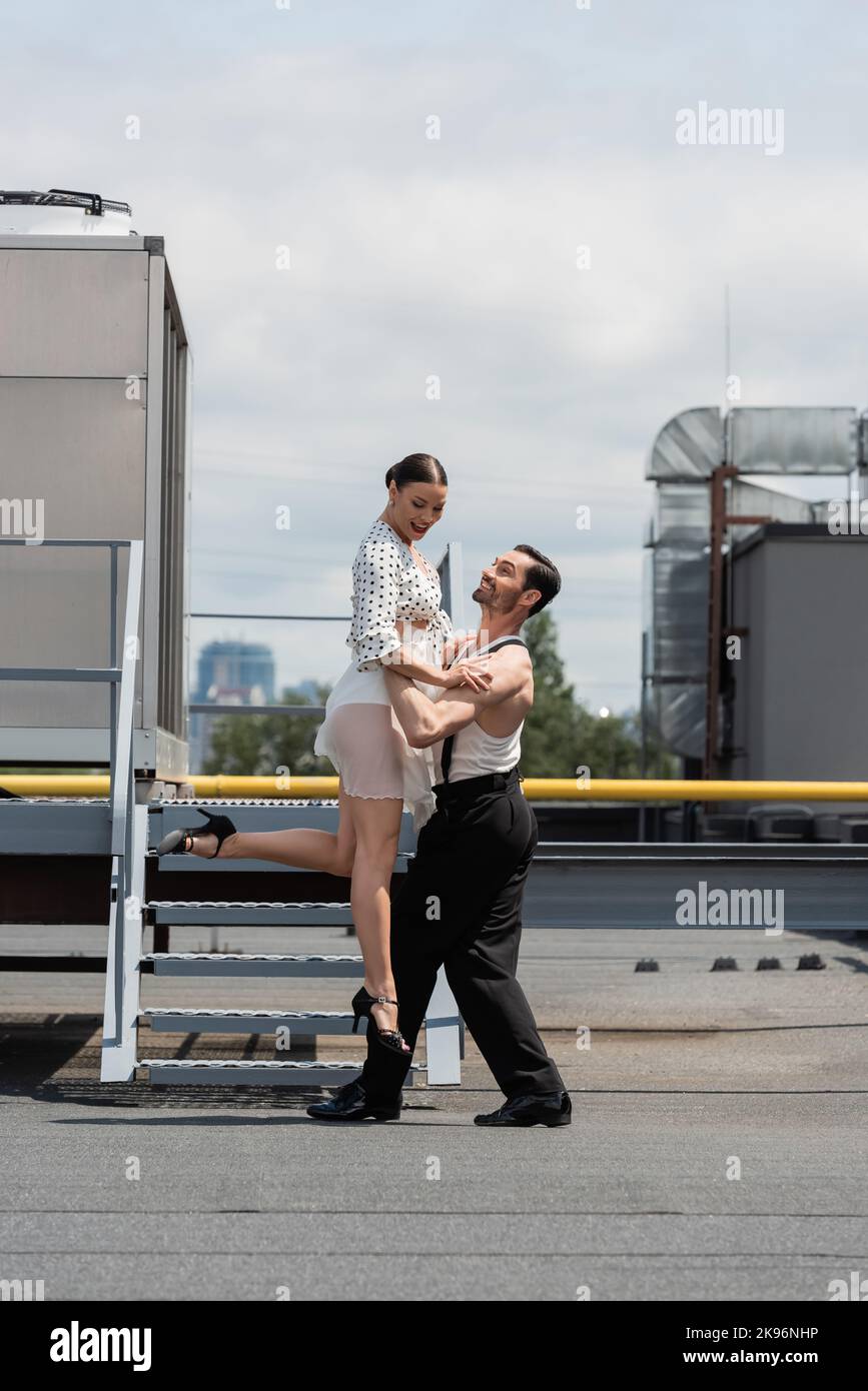 Professional dancer lifting partner while dancing on roof of building ...