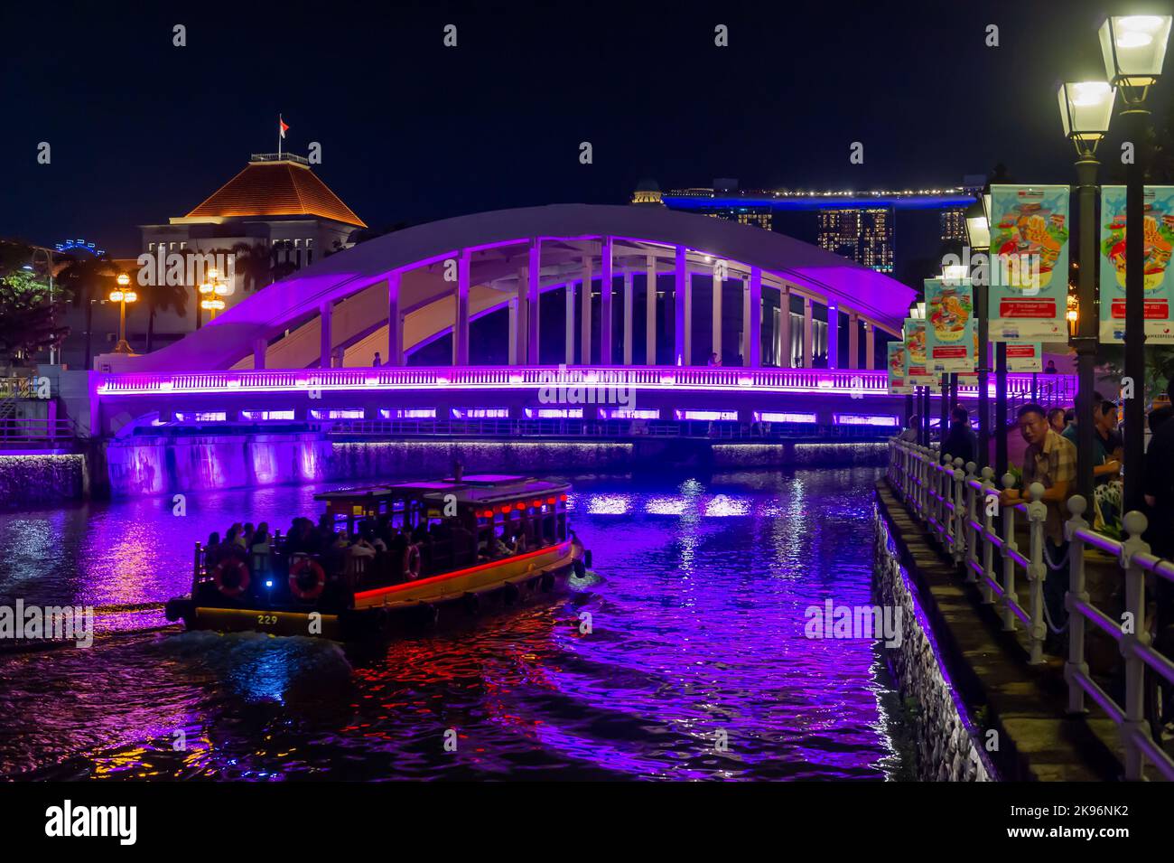 A tourist boat sailing down the Singapore River and passing under the ...