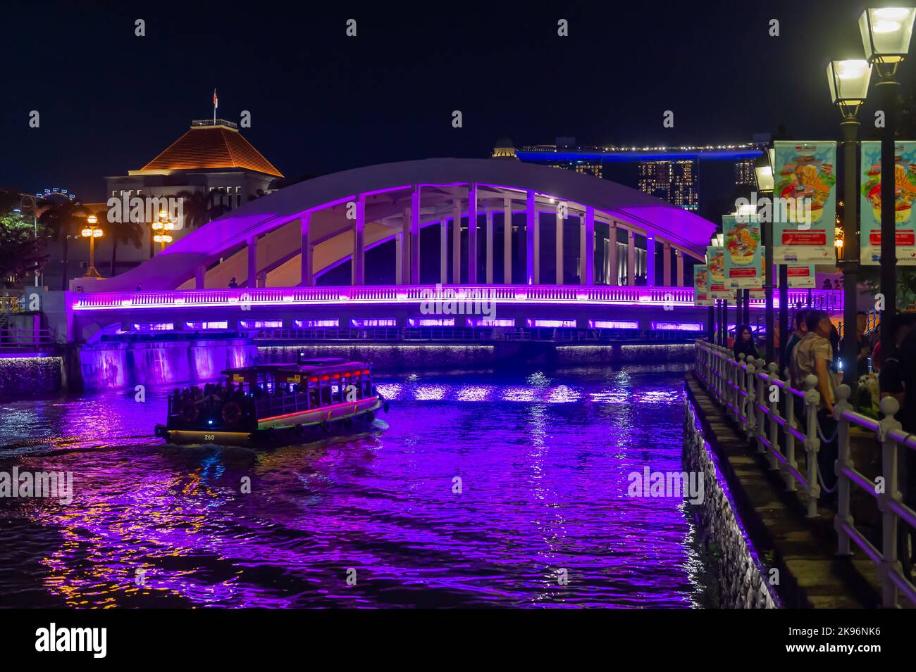 A tourist boat sailing down the Singapore River and passing under the ...