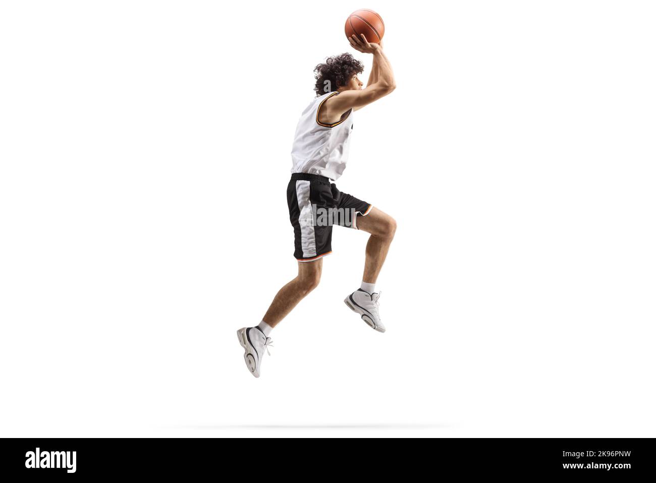 Full length shot of a basketball player up in the air shooting a ball ...