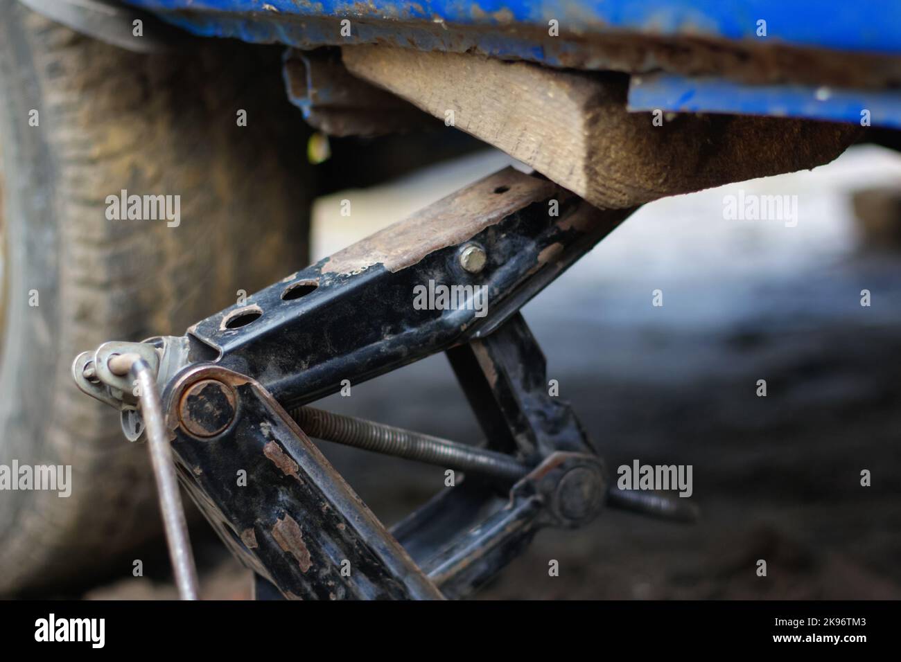Defocus closeup of a car lifted on jack in process of new wheel tire ...