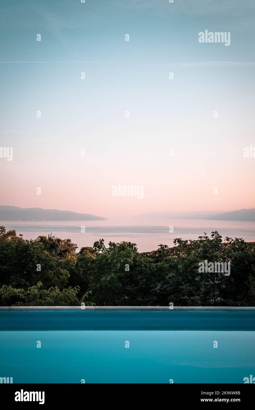 Outdoor swimming pool and green leafy shrubs by the peaceful lake at ...