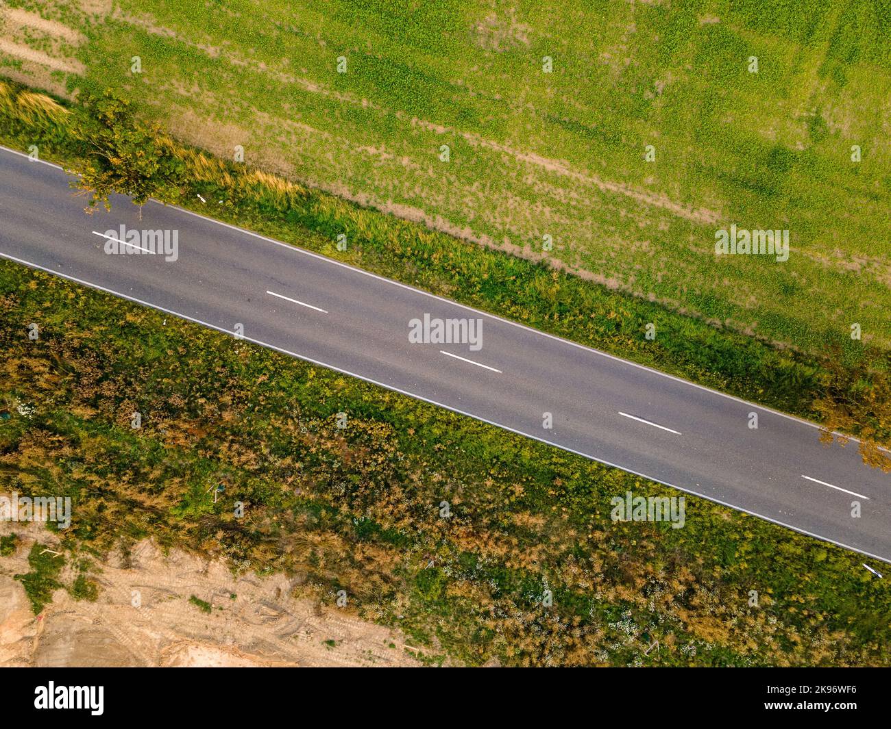 An aerial view of an asphalt road in a green meadow Stock Photo - Alamy