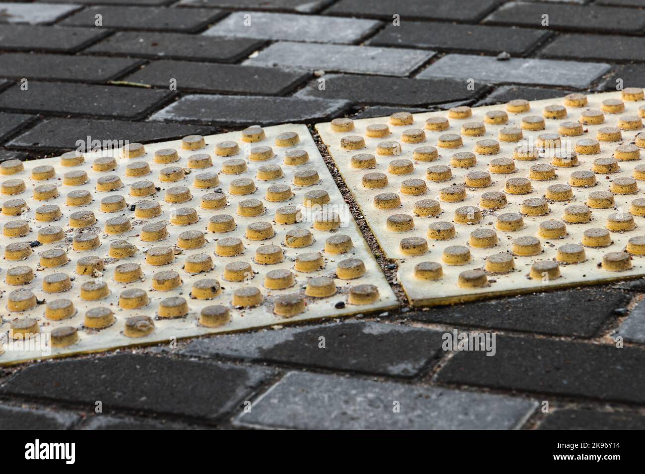 Cobbled street pavement with gray bricks and yellow tactile warning ...