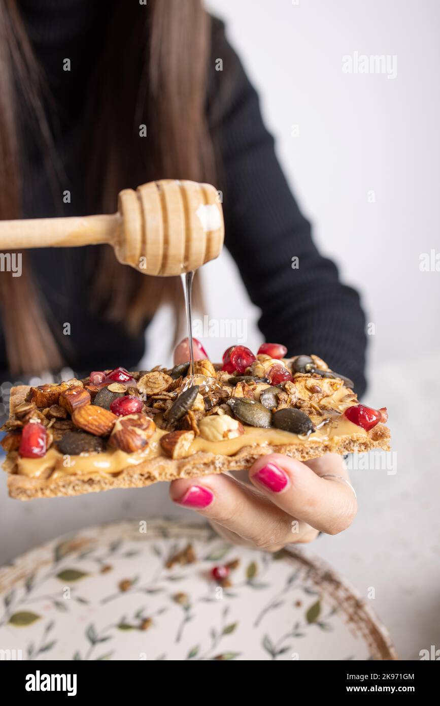 A closeup of a female hand pouring honey on a granola sandwich Stock ...