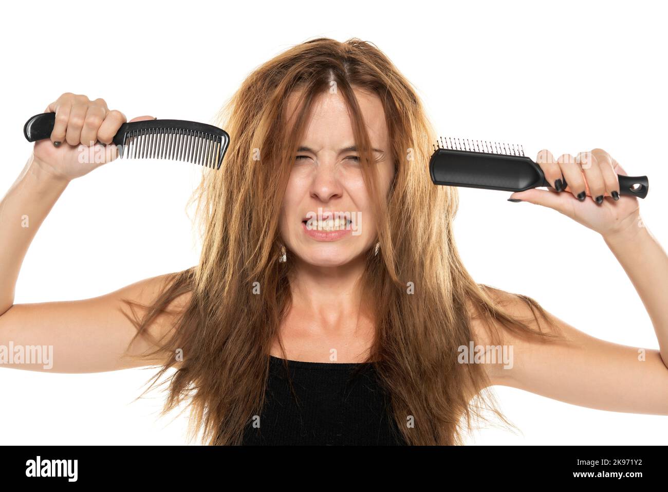 portrait of a young an woman with messy long hair holding brush and ...