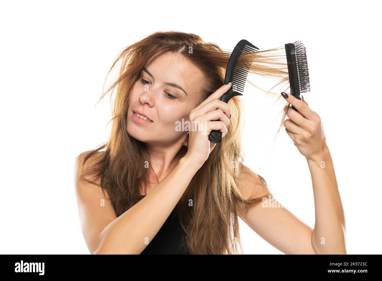 portrait of a young woman brushing her messy long hair on a white ...