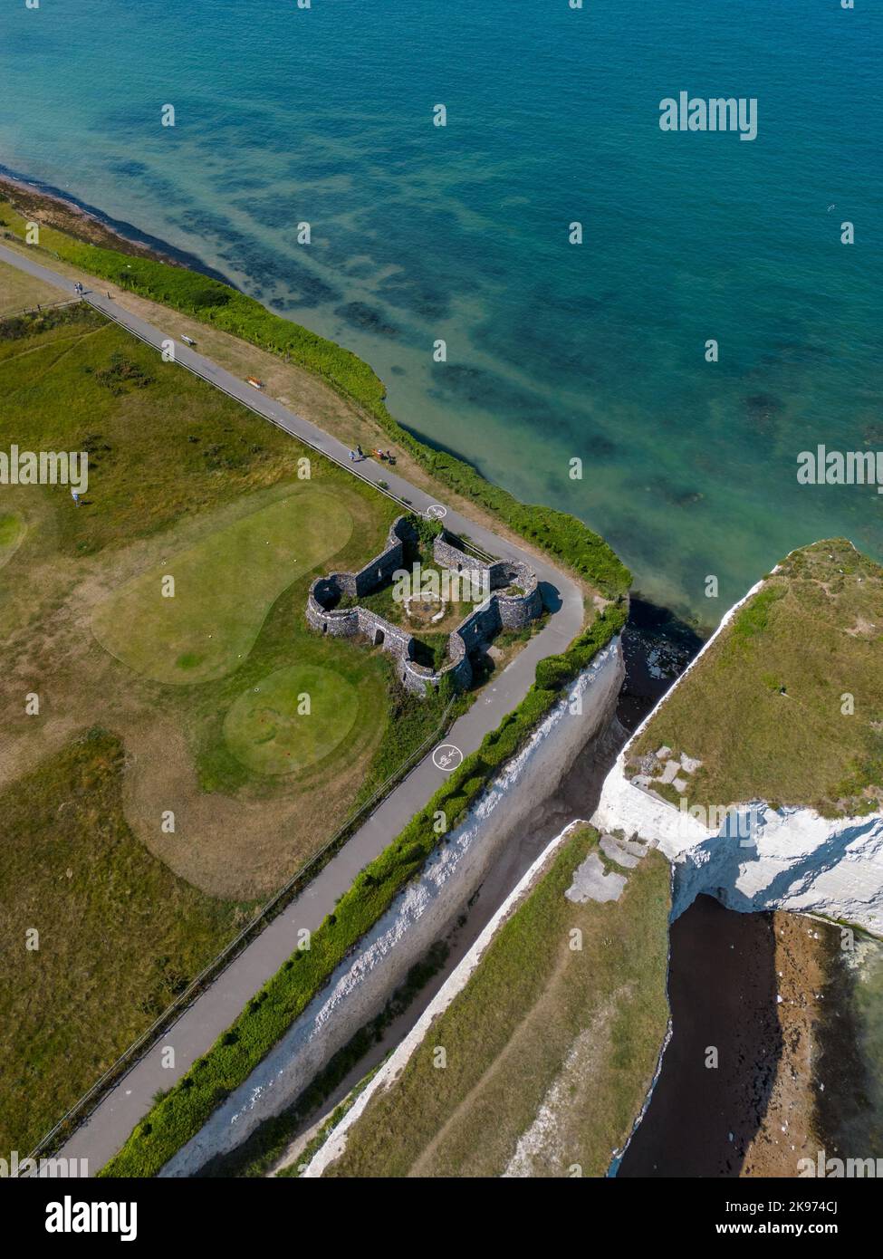 A high angle of a castle on a white chalk cliff with clear blue water ...