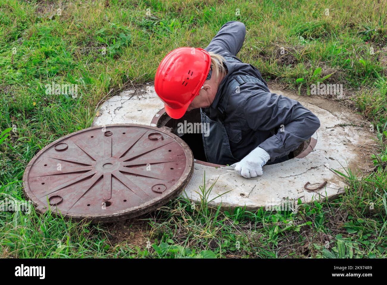 A male plumber in a helmet descended into an open water well for ...