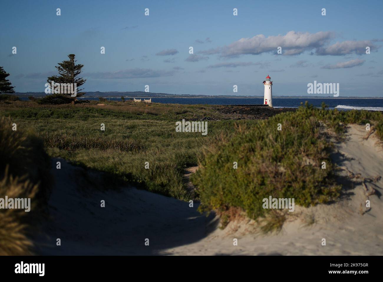 An aerial view of lighthouse surrounded by grass in background of sea ...