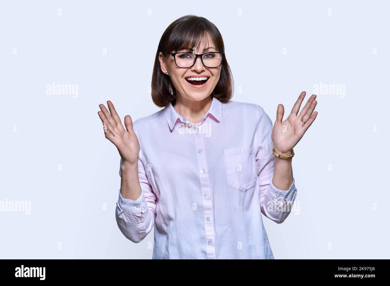 Happy emotional middle aged woman looking at camera on light background Stock Photo - Alamy