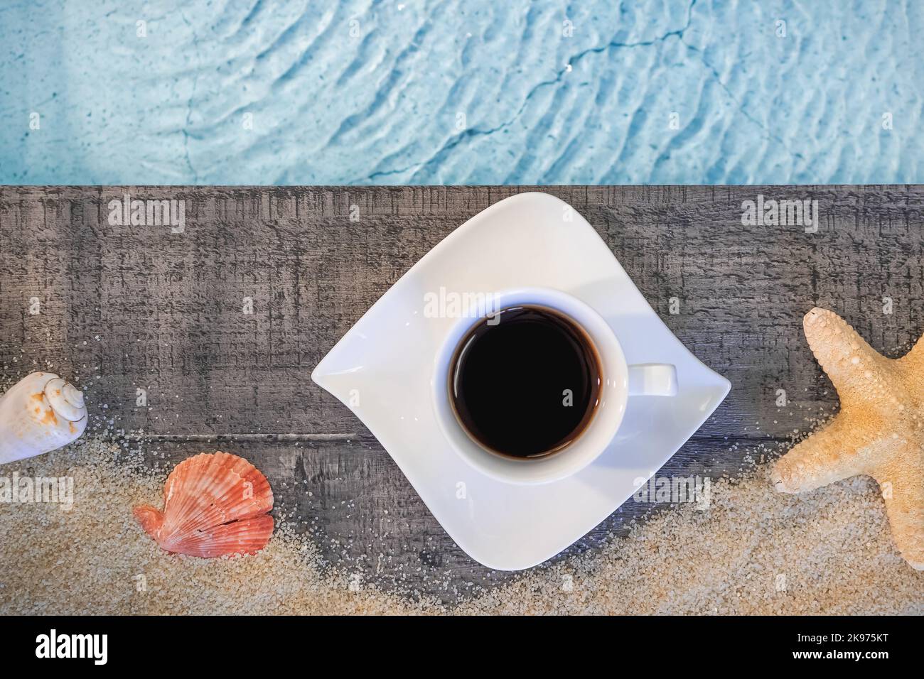 Coffee cup seen from above on a wooden pavement above a pool with a ...