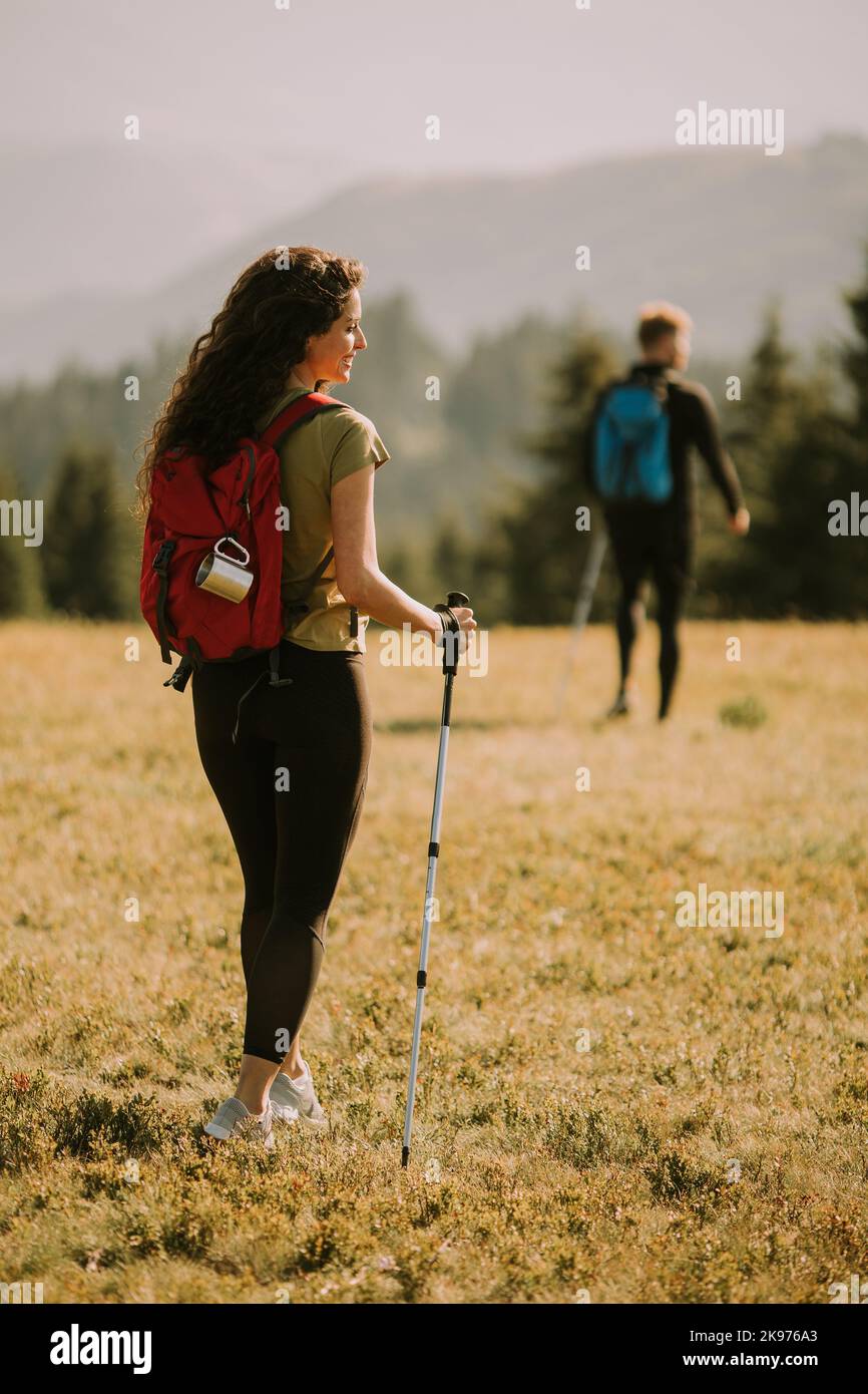 Smiling young couple walking with backpacks over green hills Stock ...