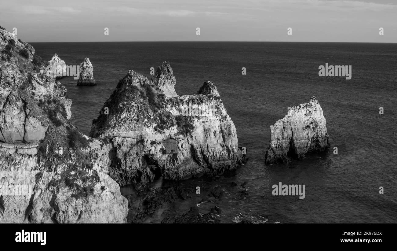 A greyscale shot of the sea rock cliffs with a cloudy sky Stock Photo ...