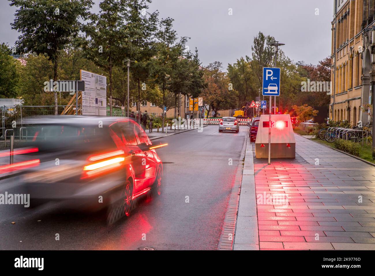 A scenery of a small street in Leipzig with few cars and traffic signs ...