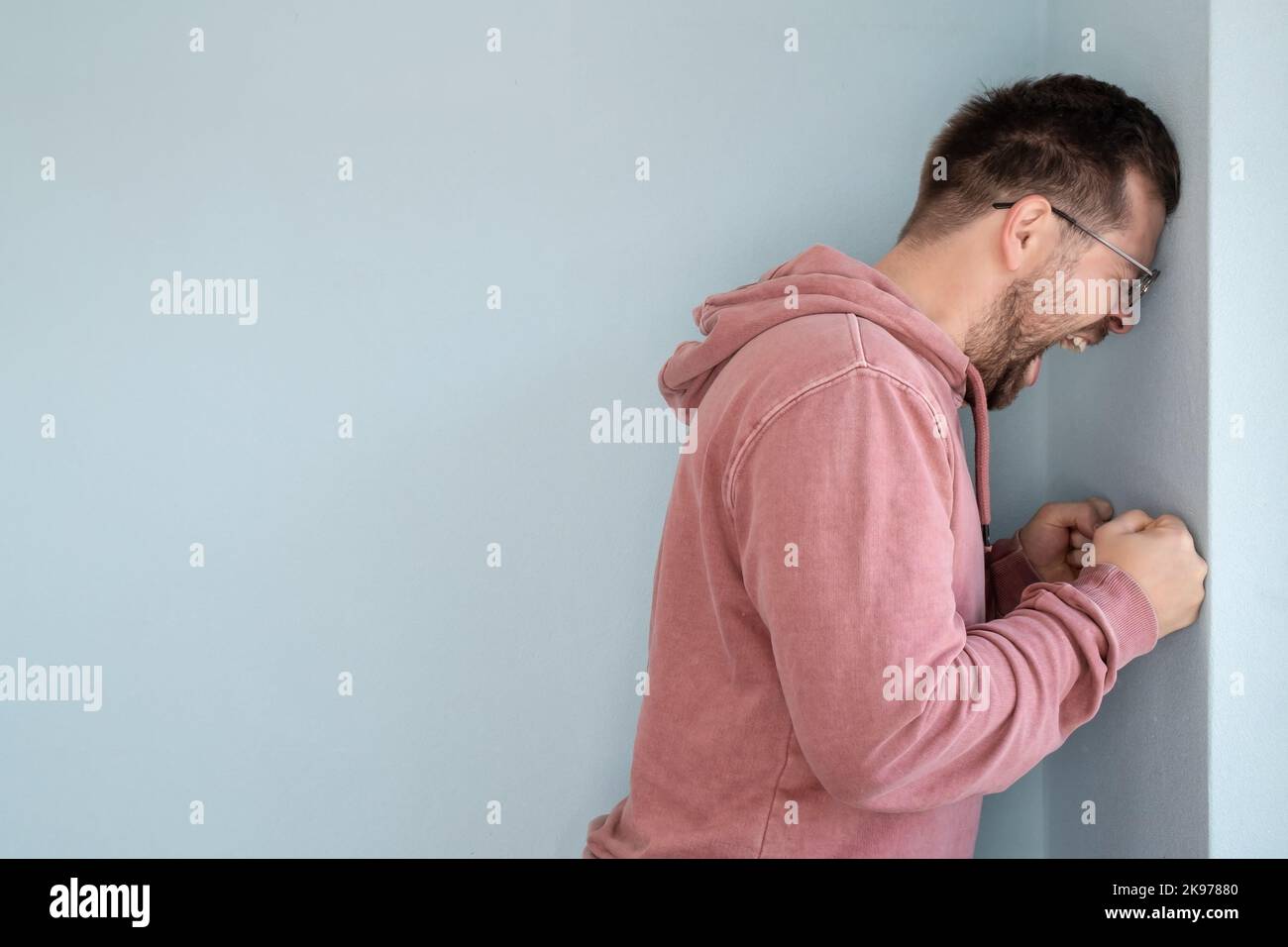 Man in stress and anger, he leaned his forehead against the wall and ...