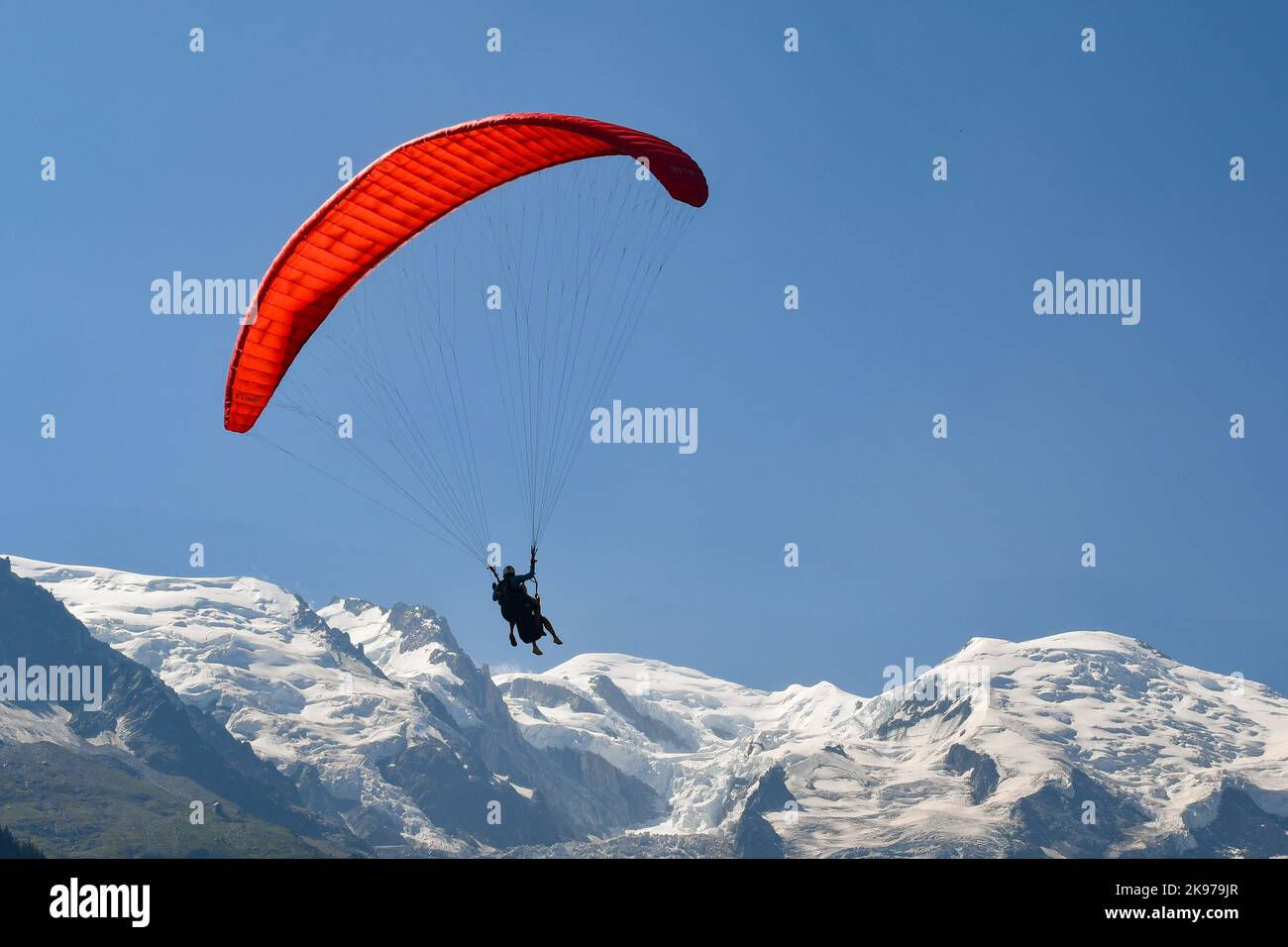 A red tandem paraglider flying in front of the Mont Blanc mountain in ...