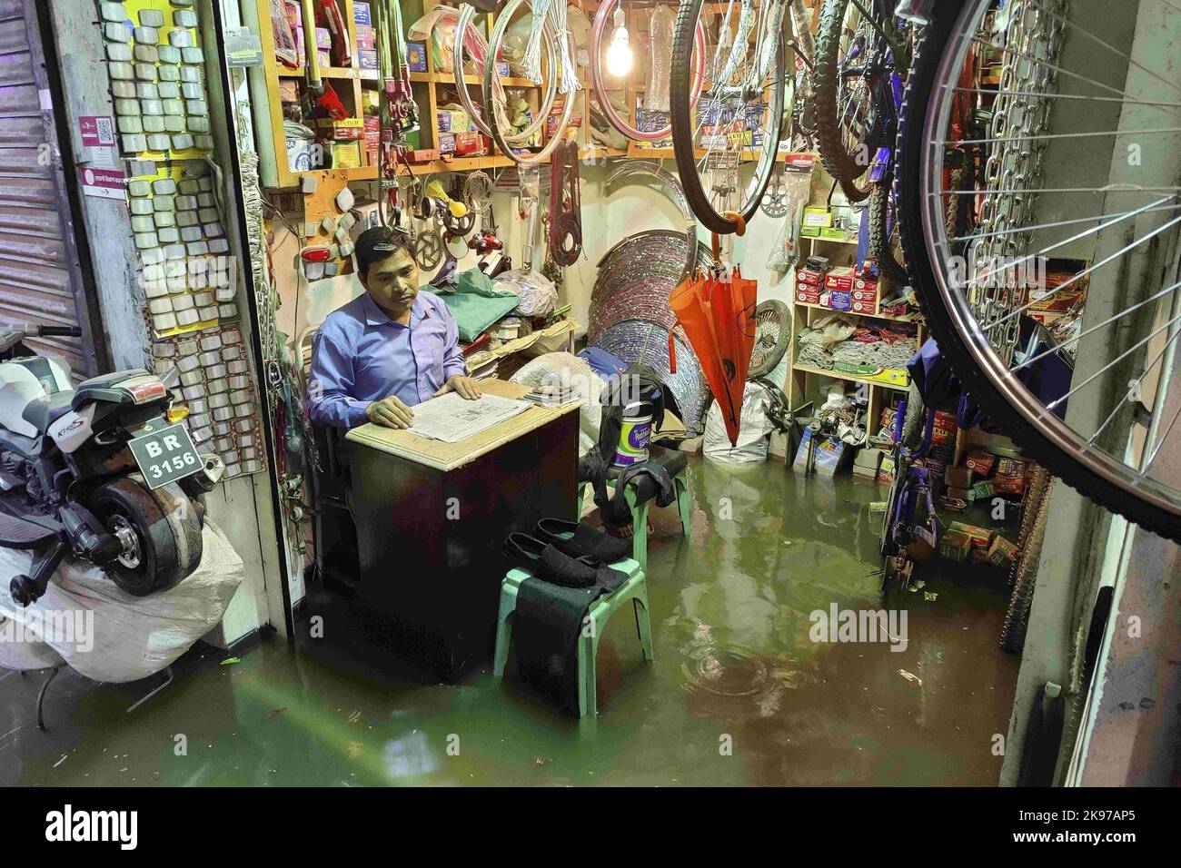 Dhaka, Bangladesh. 24th Oct, 2022. A shopkeeper sits inside his flooded ...