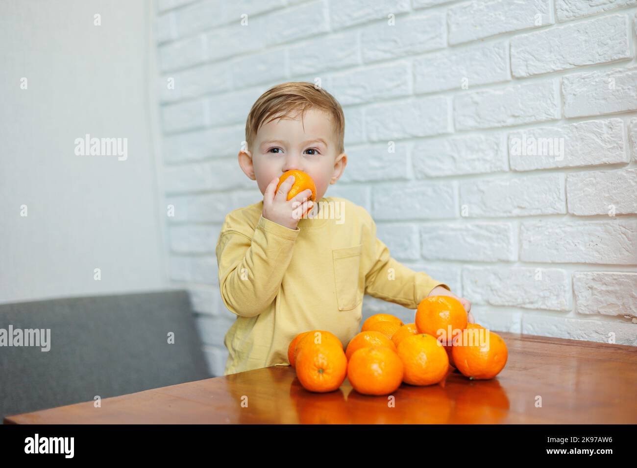 A little boy 2 years old holds tangerines in his hands. The kid wants ...