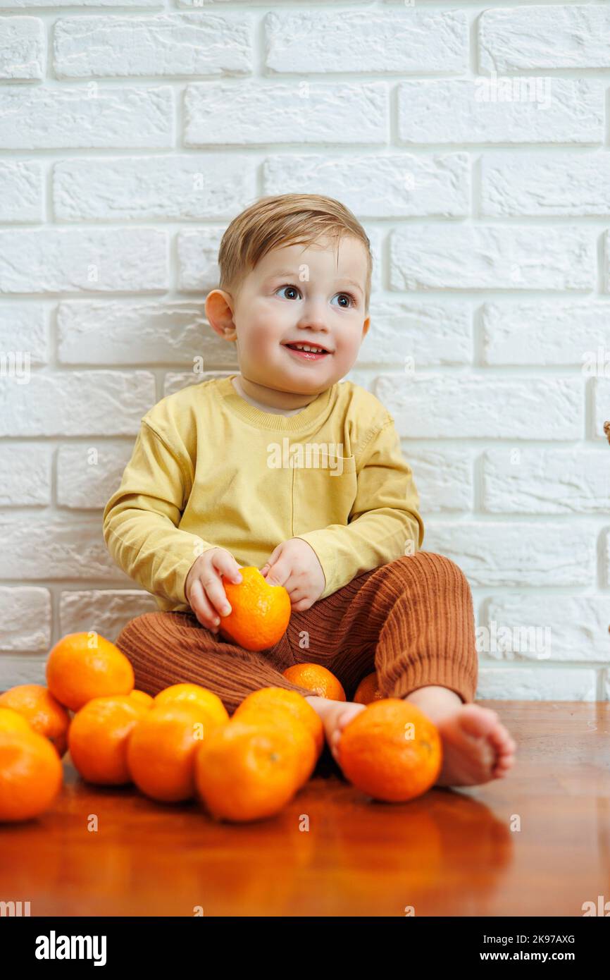 Little boy 2 years old eats tangerines. The kid wants to sit on citrus ...