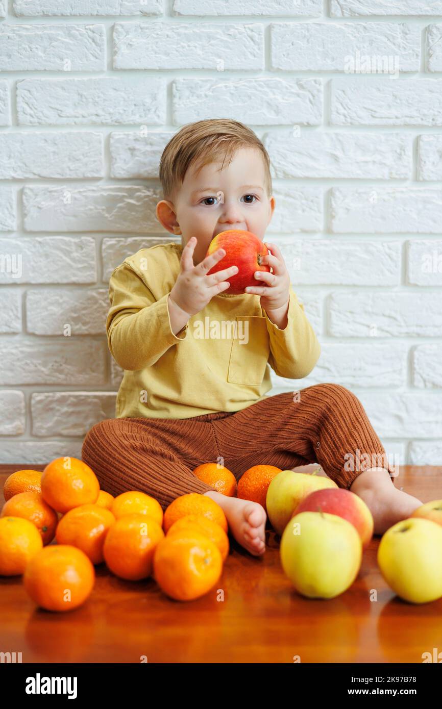 Cute smiling kid eating one fresh juicy red apple. Healthy fruits for ...