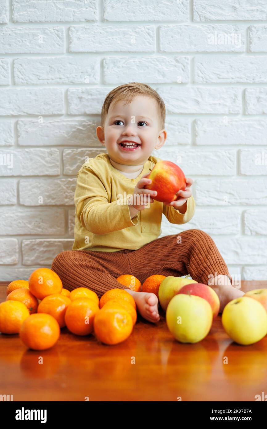 Cute smiling kid eating one fresh juicy red apple. Healthy fruits for ...