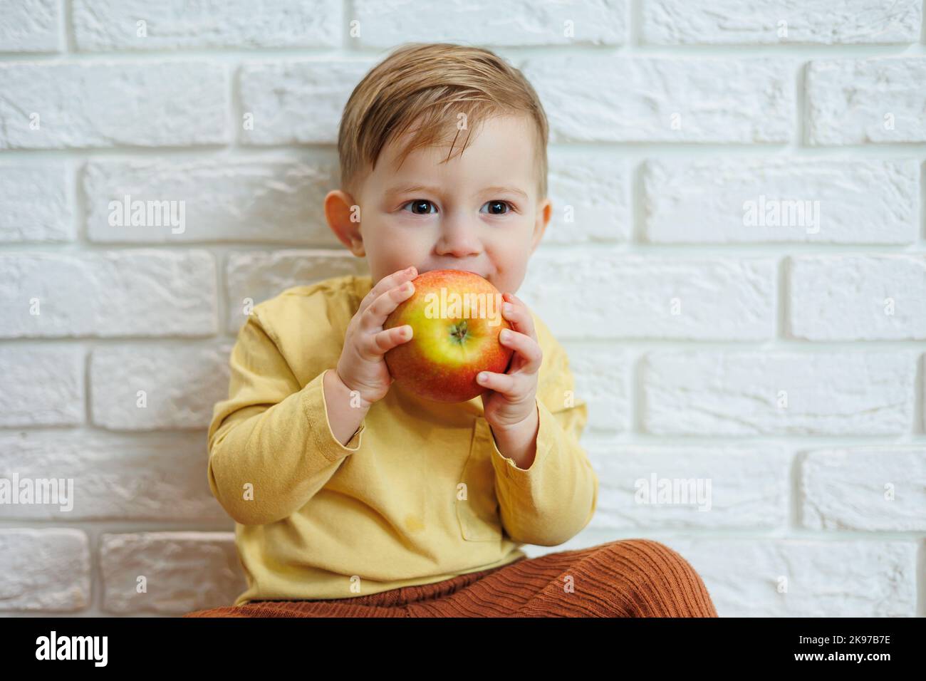 Cute smiling kid eating one fresh juicy red apple. Healthy fruits for ...