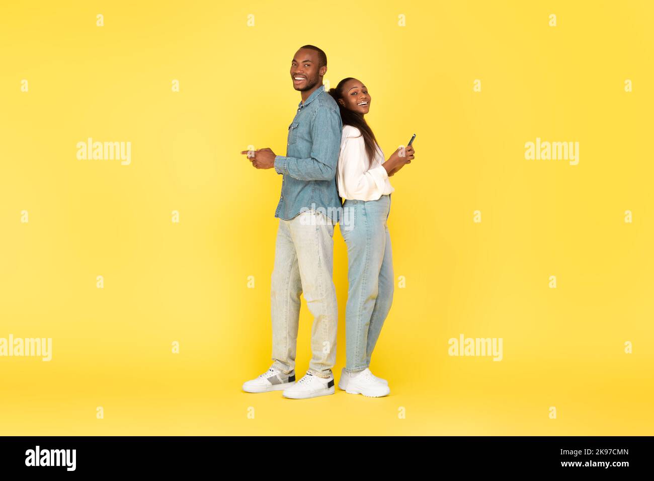 African American Couple Using Mobile Phones Texting Over Yellow ...