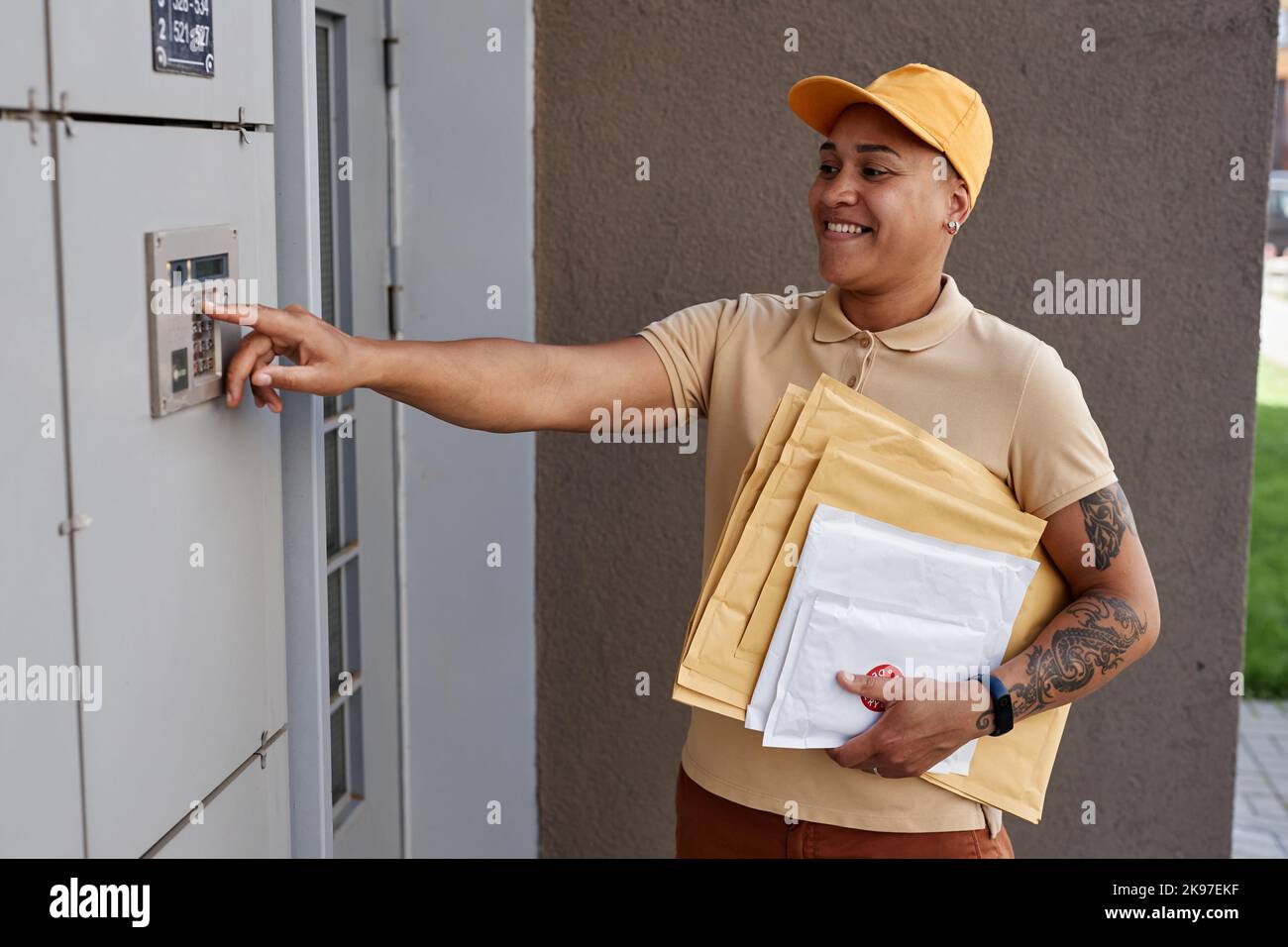 Side view portrait of female delivery worker ringing doorbell and ...