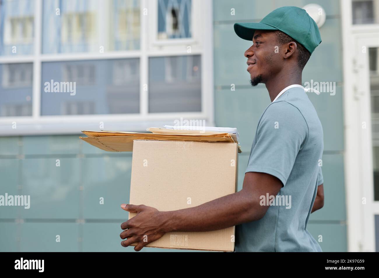 Side view portrait of young African American delivery worker holding ...