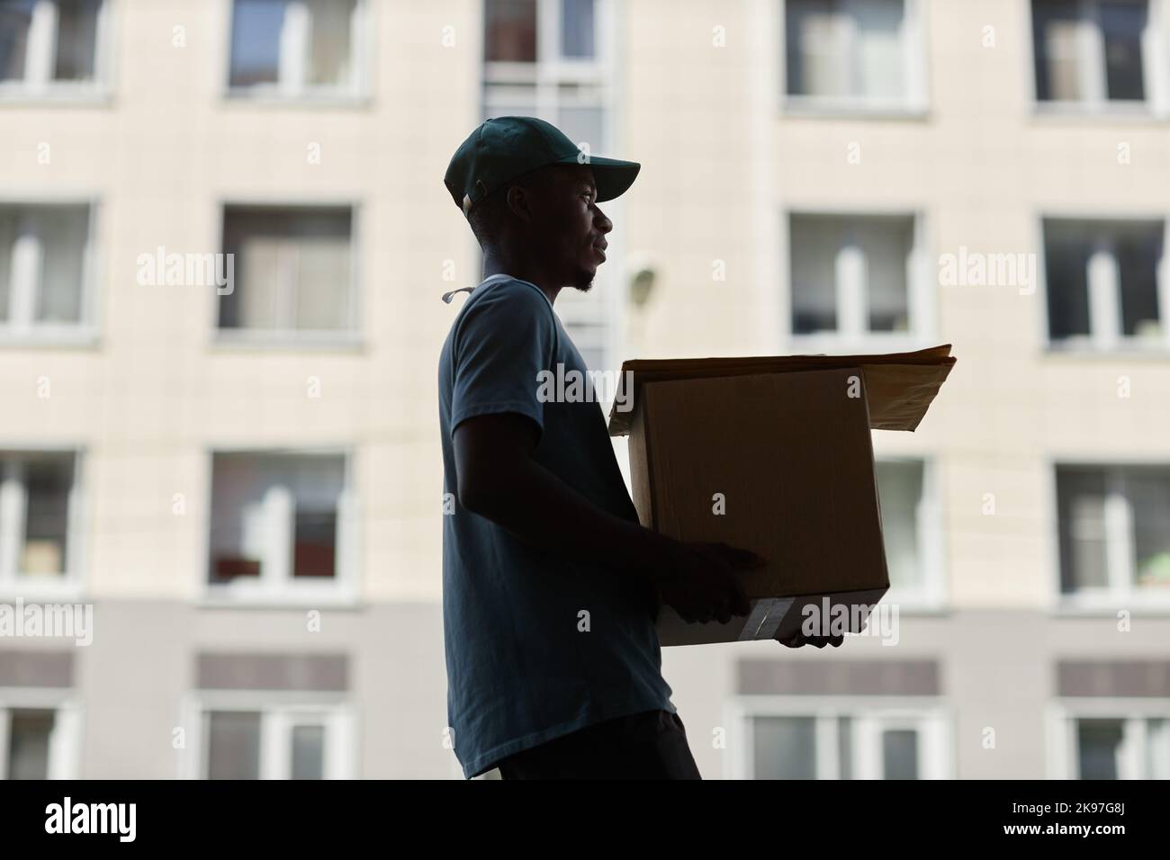 Side view portrait of young delivery worker holding box, black outline ...