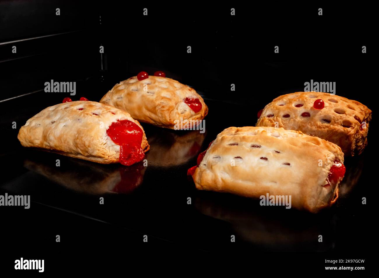 Four baked homemade buns with red strawberry jam in electric oven Stock ...