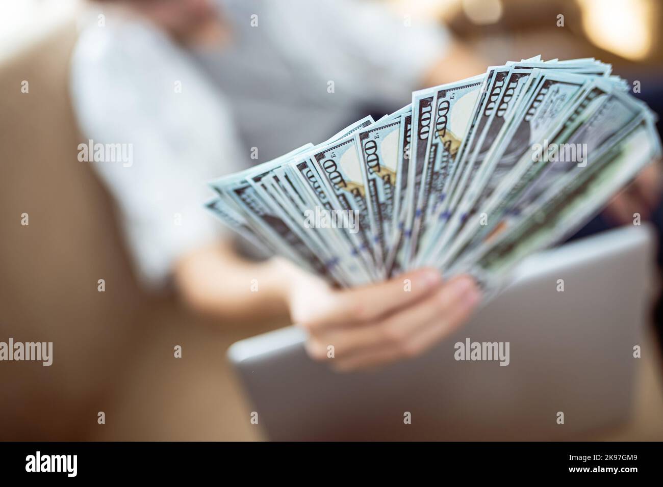 A fan of hundred-dollar bills in the hands of a teenager. The student ...