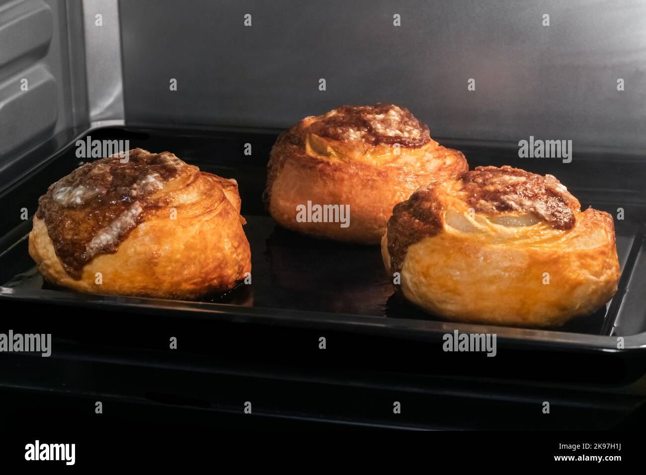 Three baked cinnamon buns in electric oven at home Stock Photo - Alamy