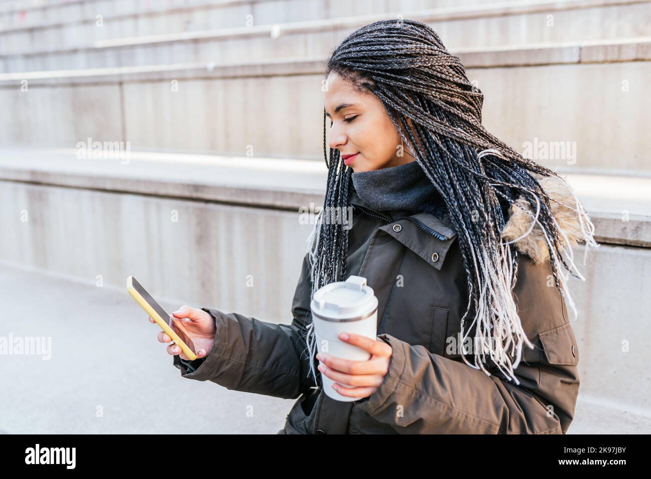 Side view of Hispanic female with dreadlocks browsing modern cellphone ...