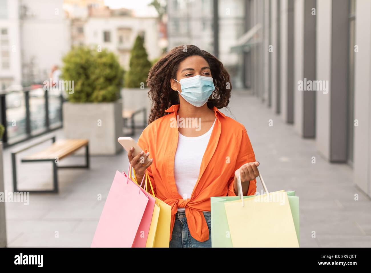 Happy young african american woman in casual, protective mask with many ...