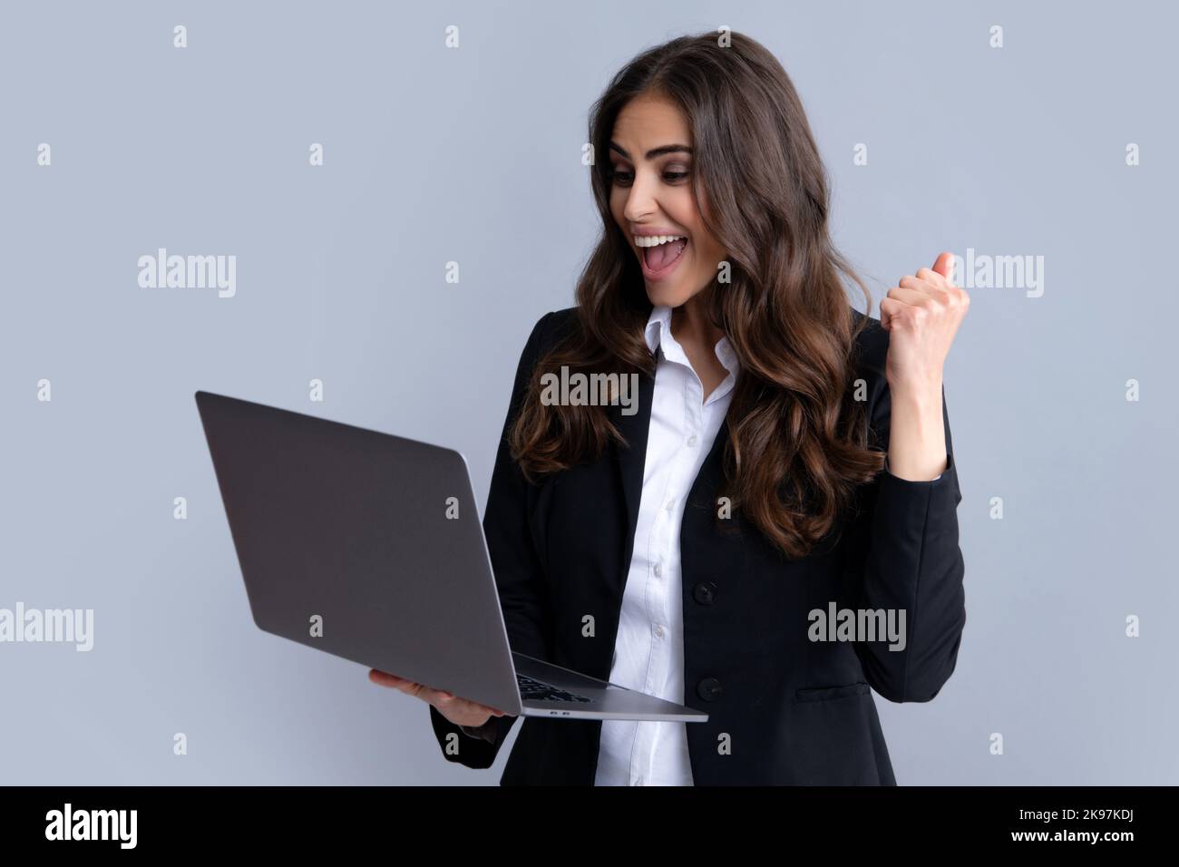 Beautiful smiling business woman over grey background using laptop ...