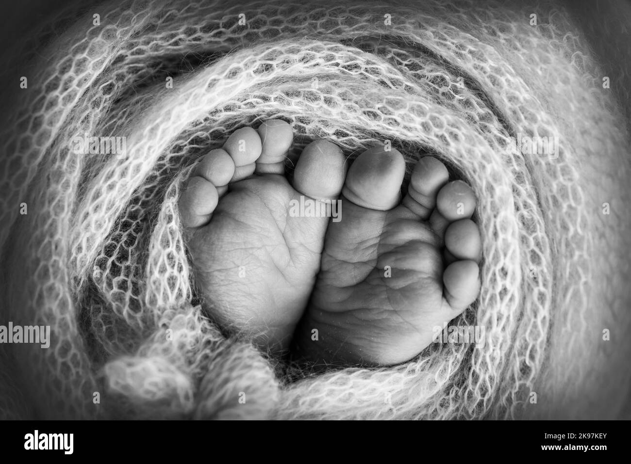 Soft feet of a newborn in a woolen blanket. Close up of toes, heels and ...