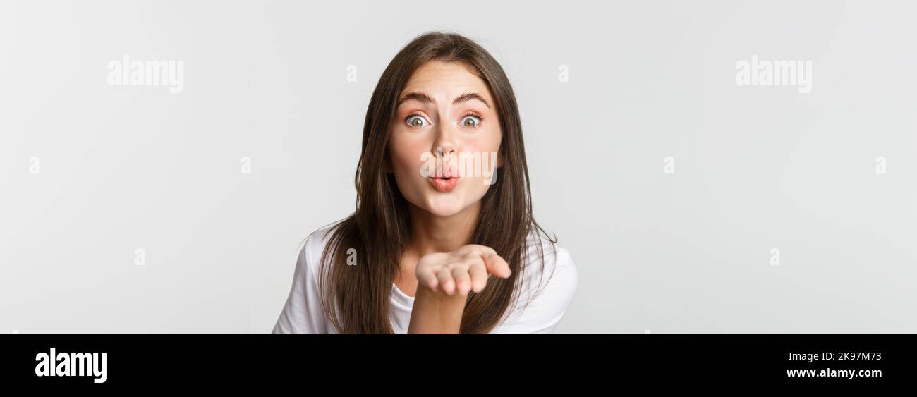 Close-up of beautiful flirty girl pouting lips and sending air kiss at ...