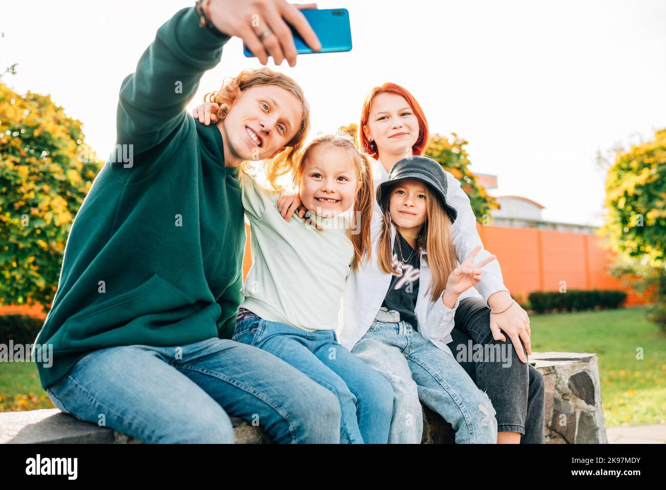 Portraits of three smiling sisters and brother teen taking selfie ...