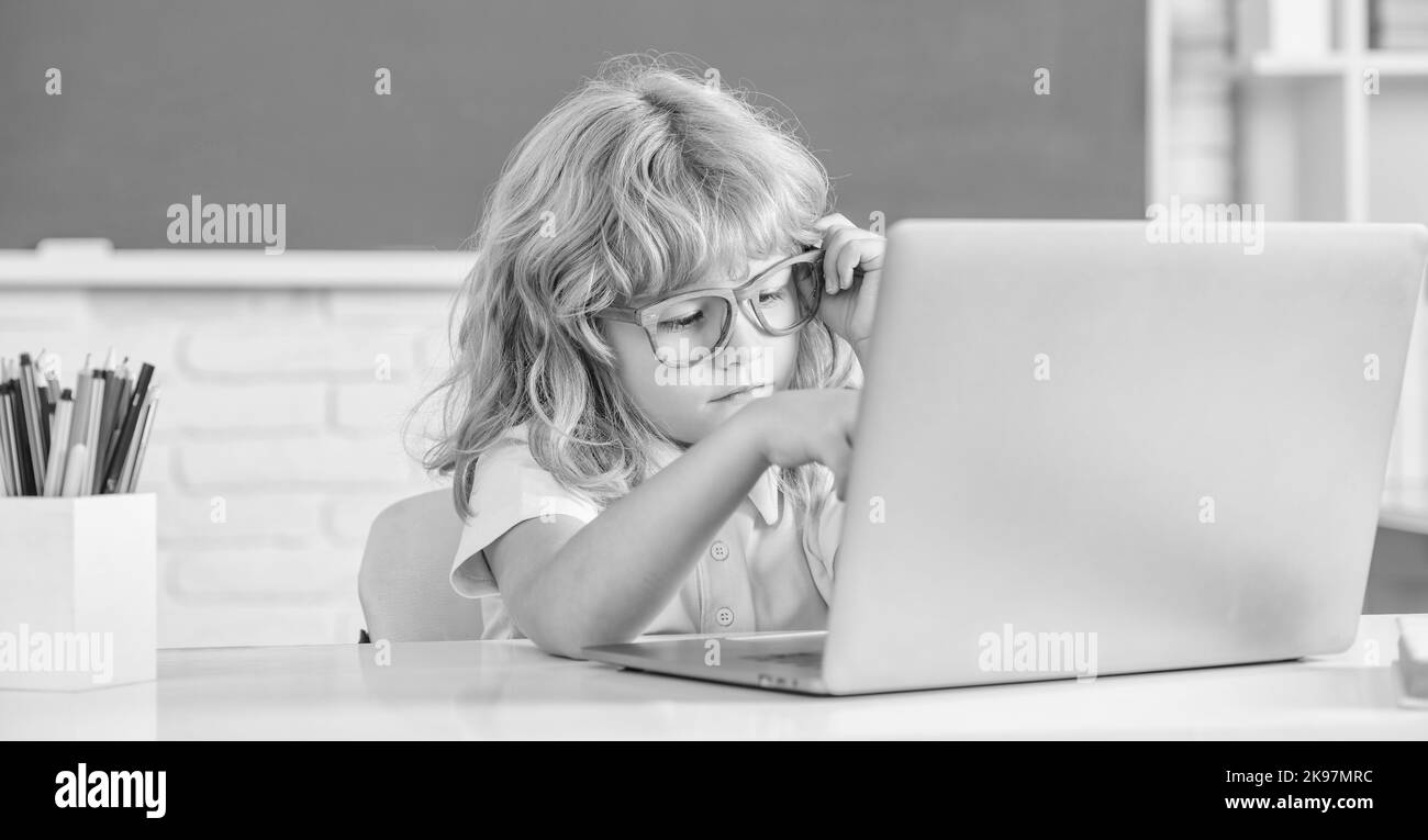 busy kid boy in glasses study online in school classrrom with computer ...